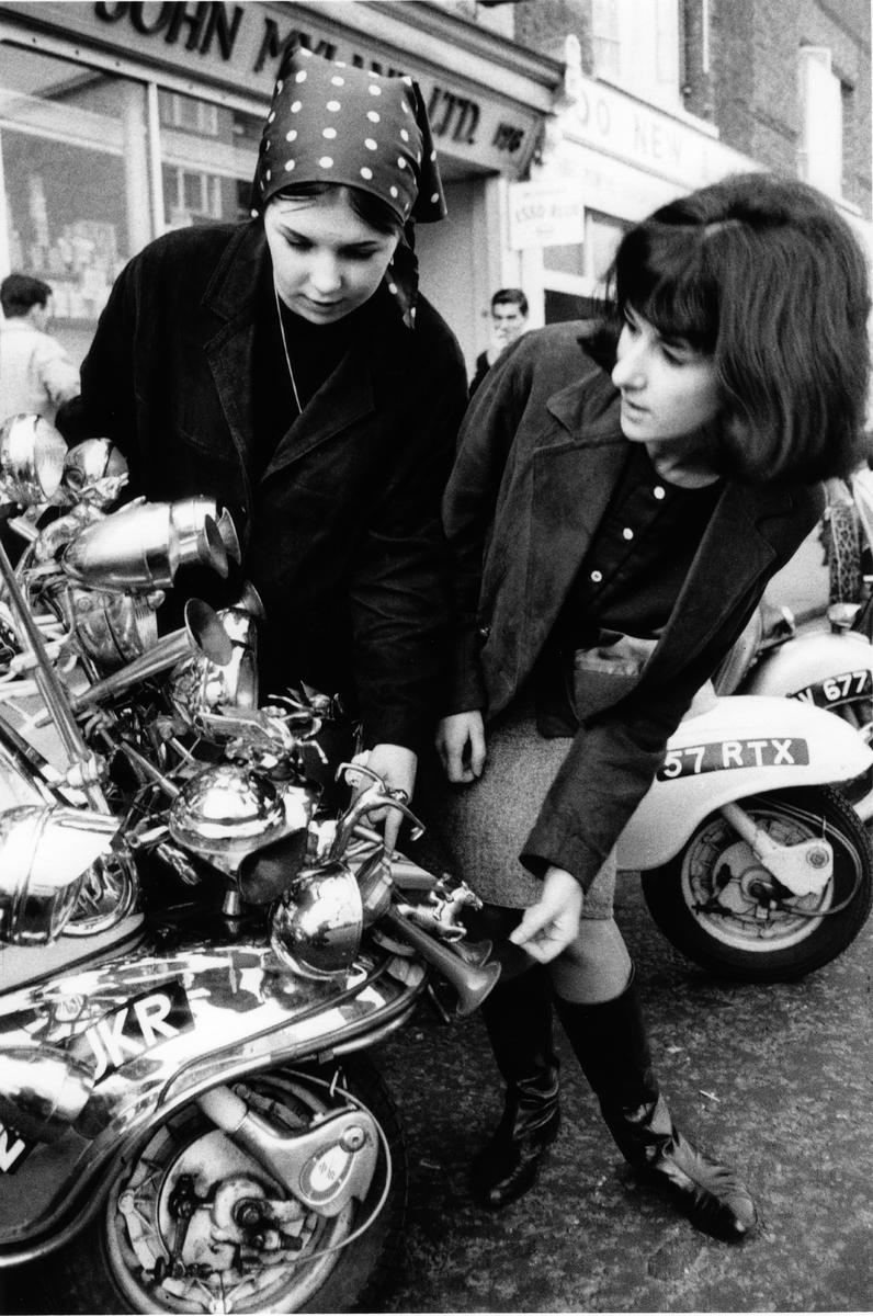 Two teenage 'Mod' girls admiring a light-and-horn-festooned scooter in ...
