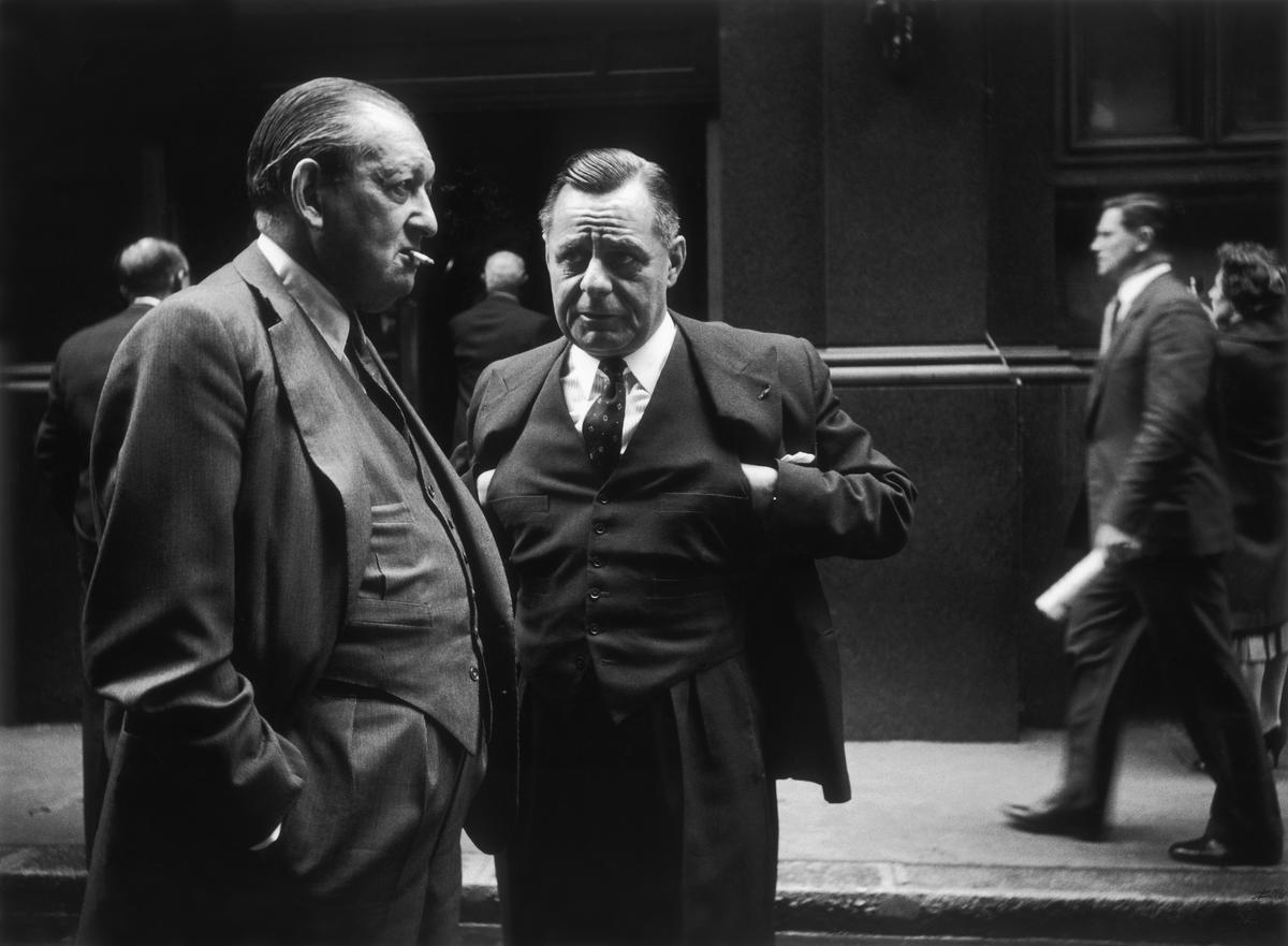 Two suited city gentlemen stand talking on street | London Museum