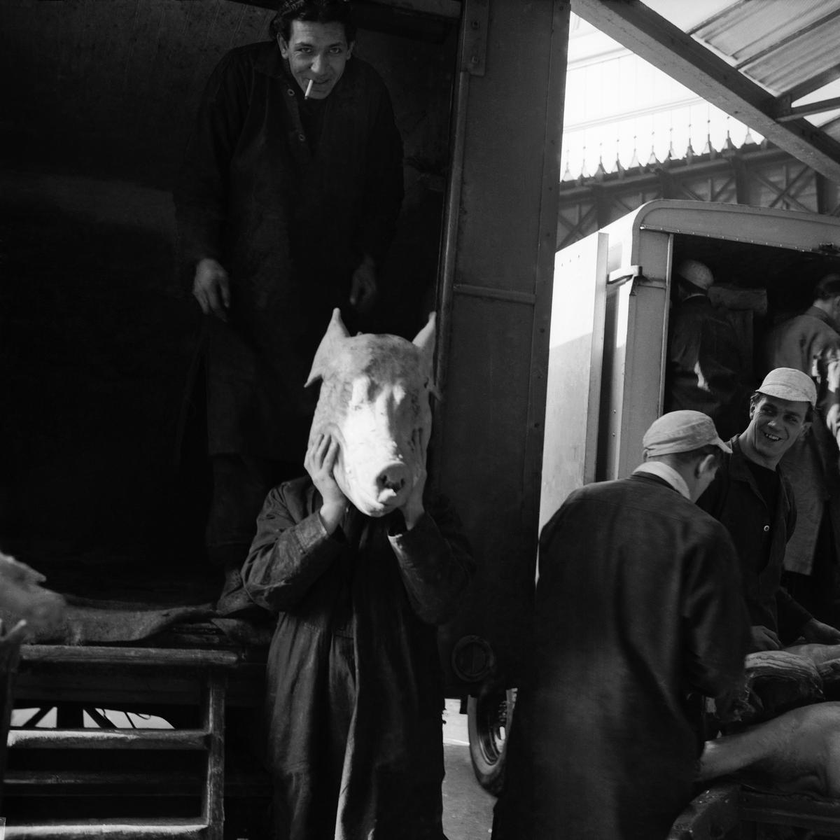 A meat porter at Smithfield poses with a pig's head | London Museum