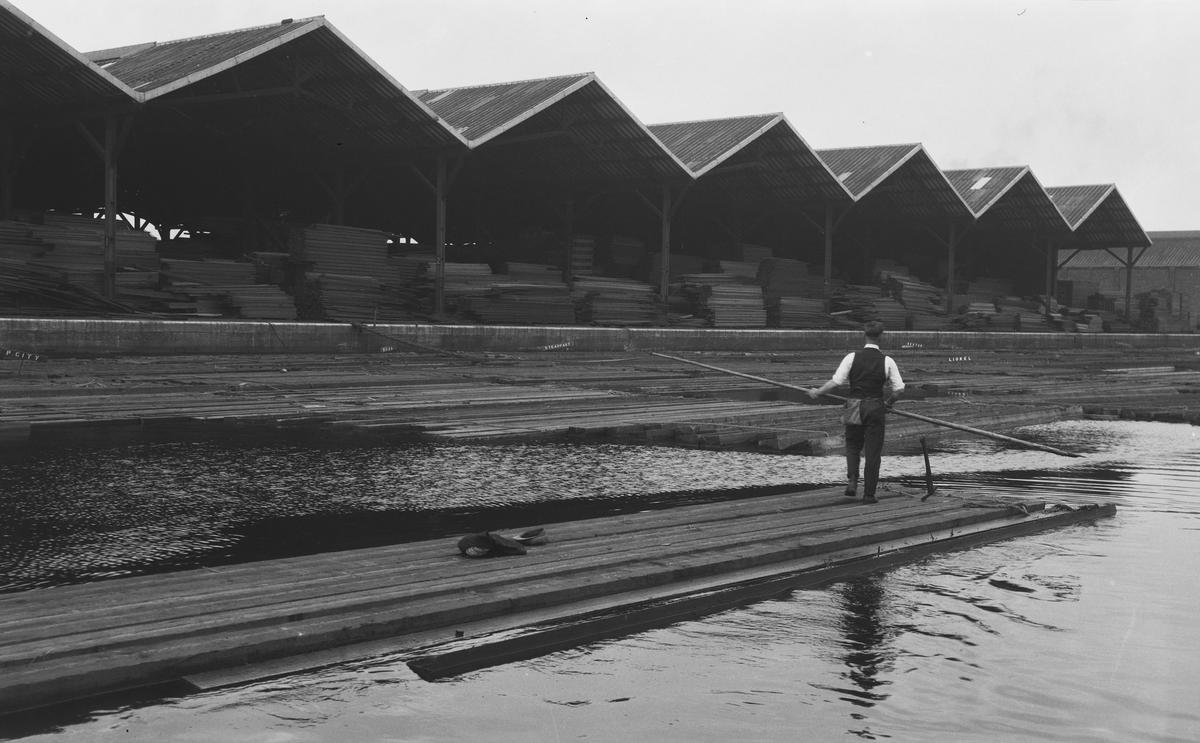Surrey Docks: Timber rafter using a pole to navigate floating raft from ...