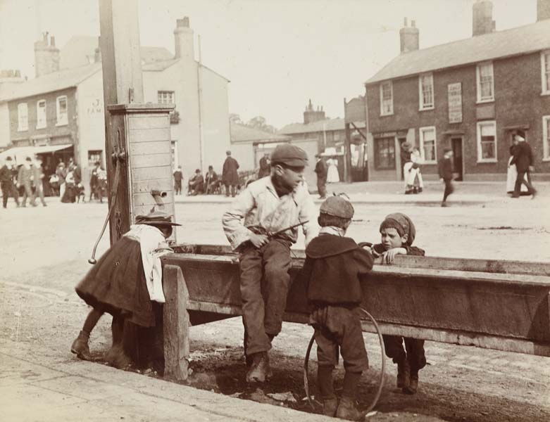 Children playing at a water trough in Barnet High Street | London Museum